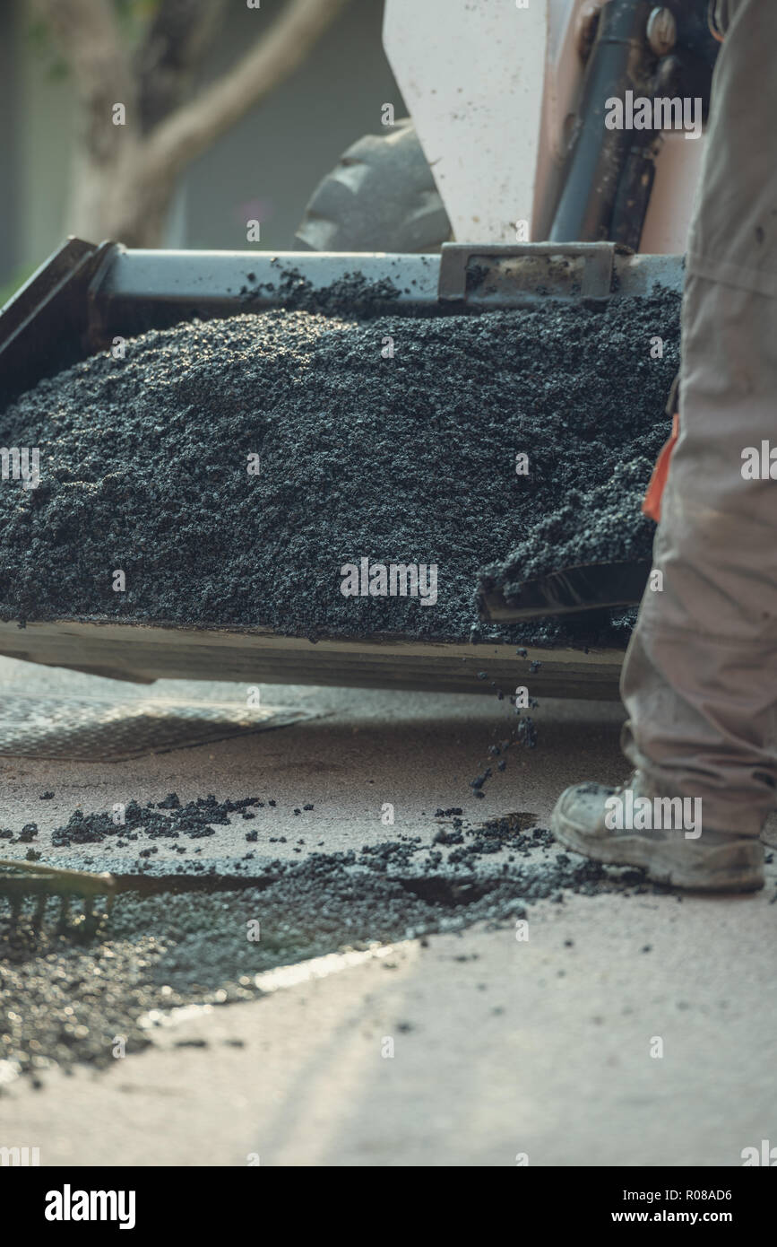 Retro image of a worker taking asphalt mix with a shovel from a ...