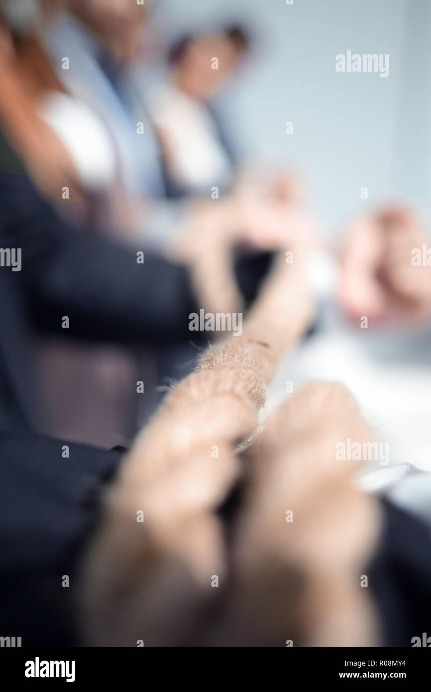 People holding rope together on light background, closeup of hands ...