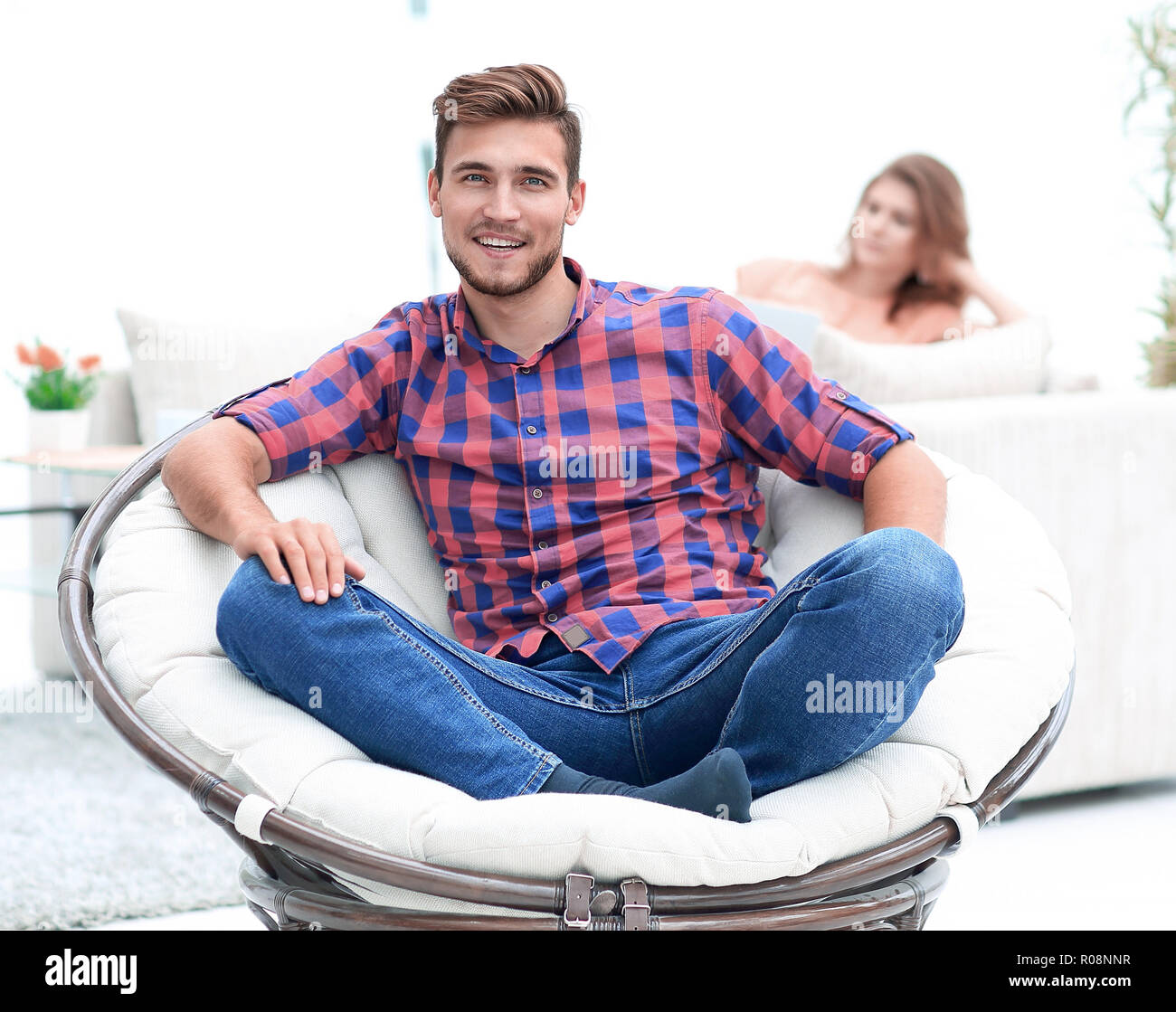 modern young man sitting in a big round chair on blurred background ...