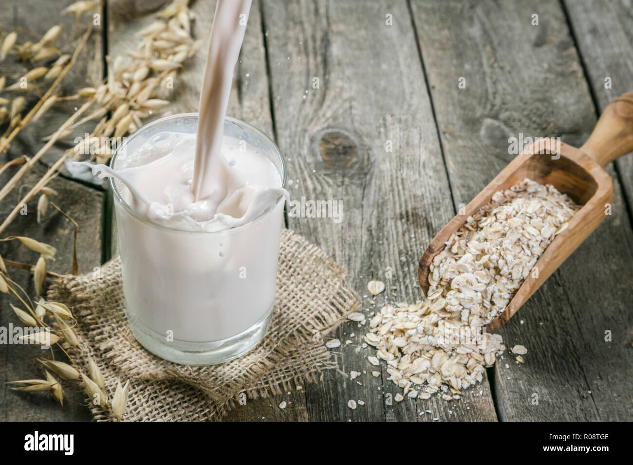 Pouring oat milk on rustic wood background, copy space Stock Photo - Alamy