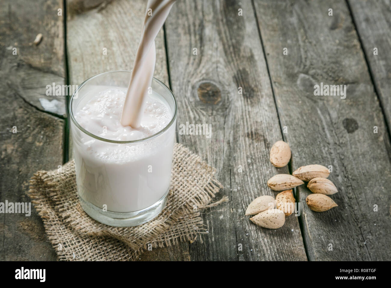 Pouring almond milk on rustic wood background, copy space Stock Photo ...