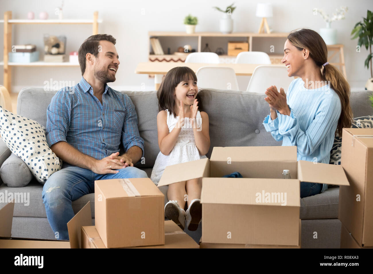 Happy family sitting on couch at new home Stock Photo - Alamy