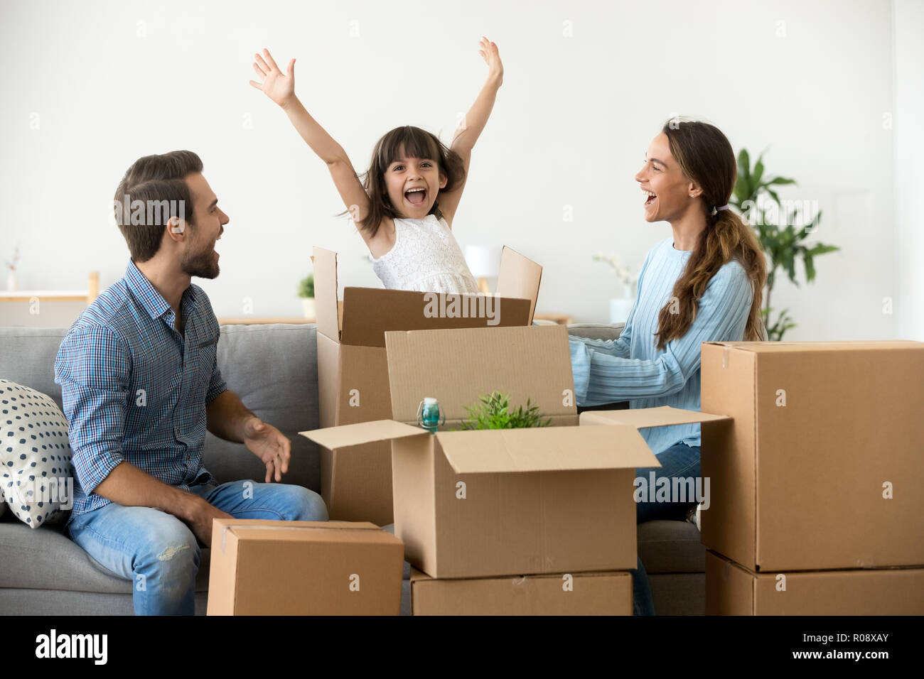 Funny daughter jumping out of carton box playing with parents Stock ...