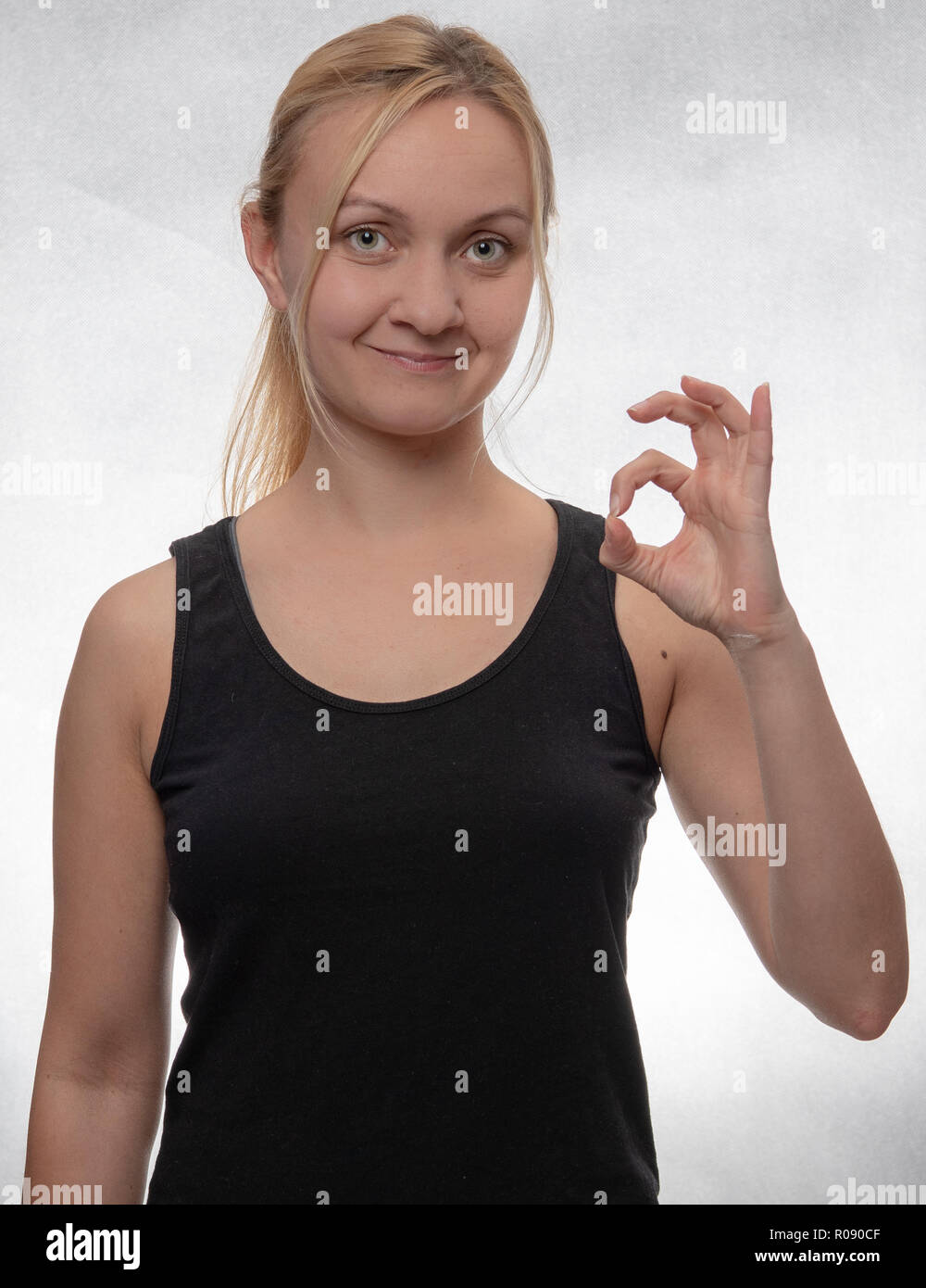 young woman in black tank top showing OK sign Stock Photo - Alamy