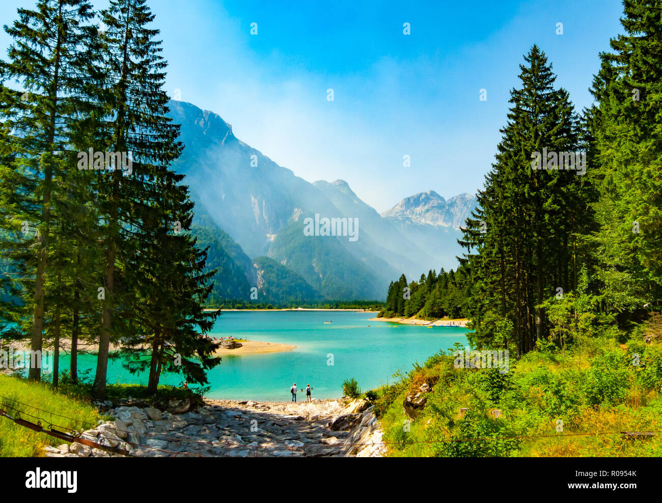 Cave del Predil lake framed by fir trees with haze embracing mountain ...