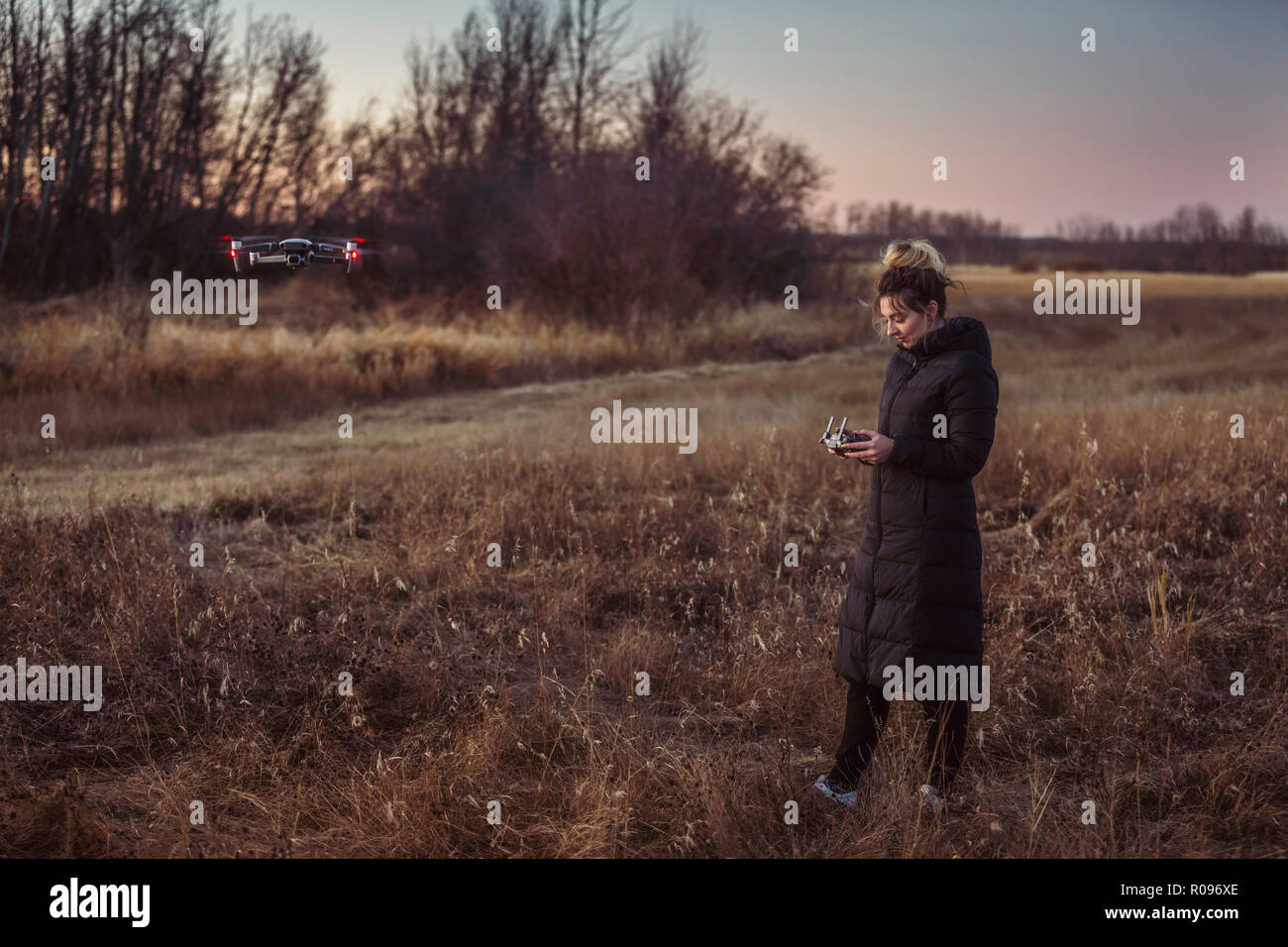 Female drone pilot looks at her remote controller while operating in a ...