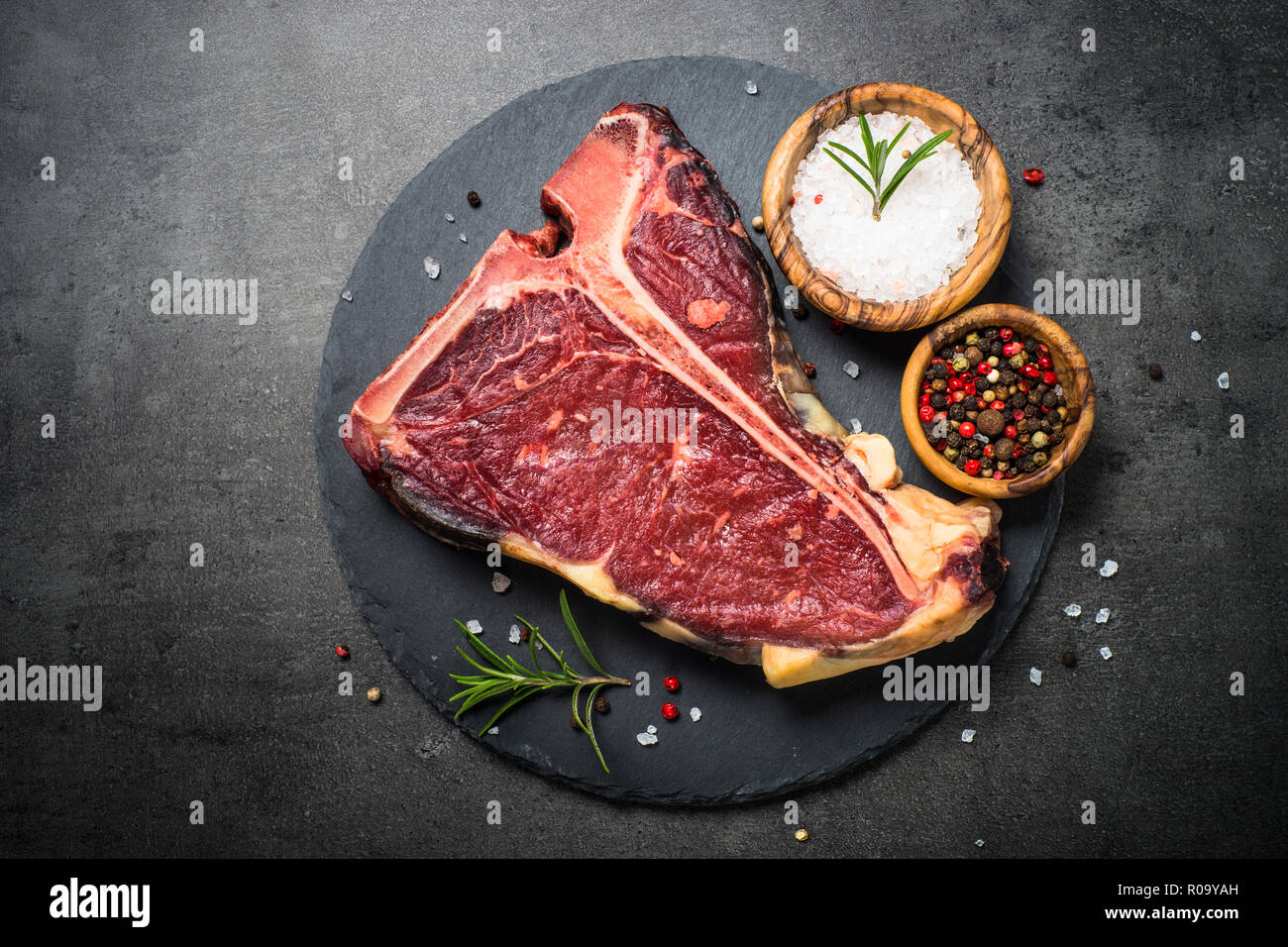 T-bone beef steak on black background with spices. Ready for cooking ...