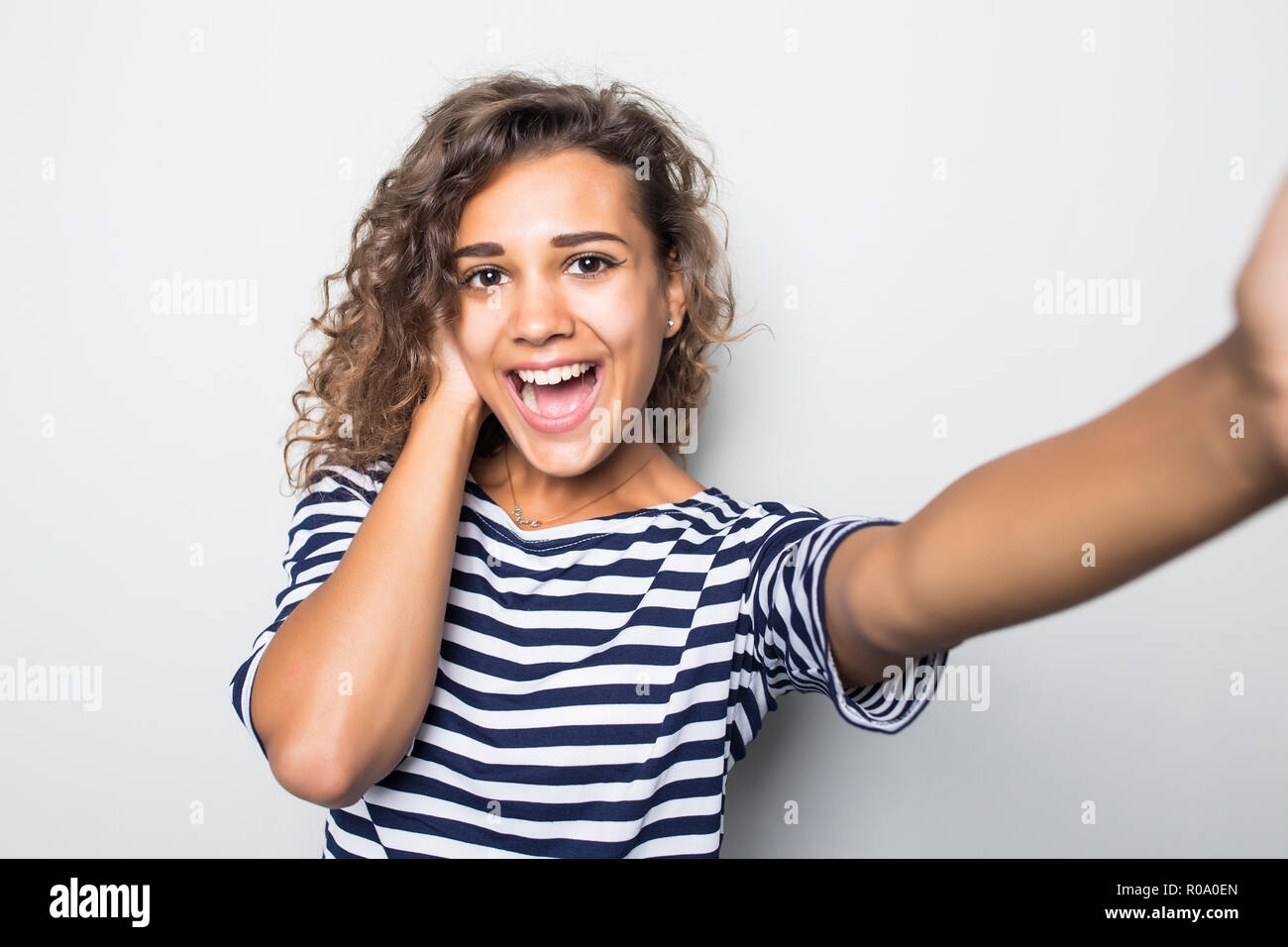 Portrait of a young mixed race mulatto woman taking selfie with mobile ...