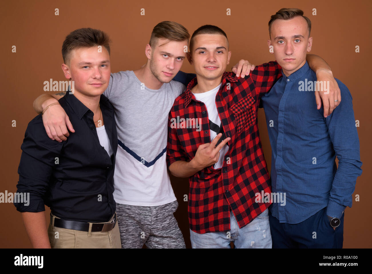 Four young handsome men together against brown background Stock Photo ...