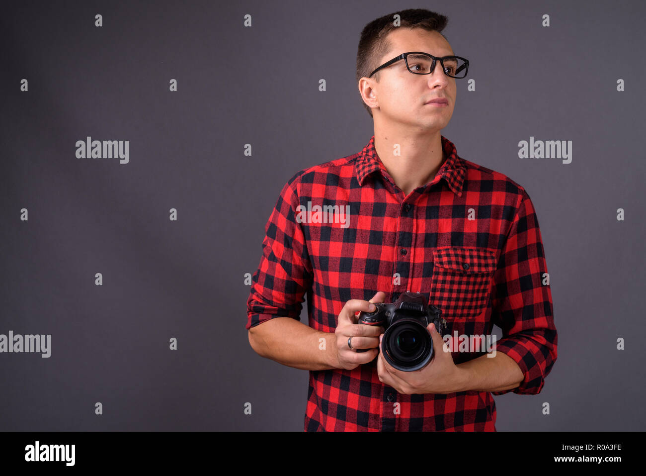 Portrait of young handsome man photographer holding camera Stock Photo ...