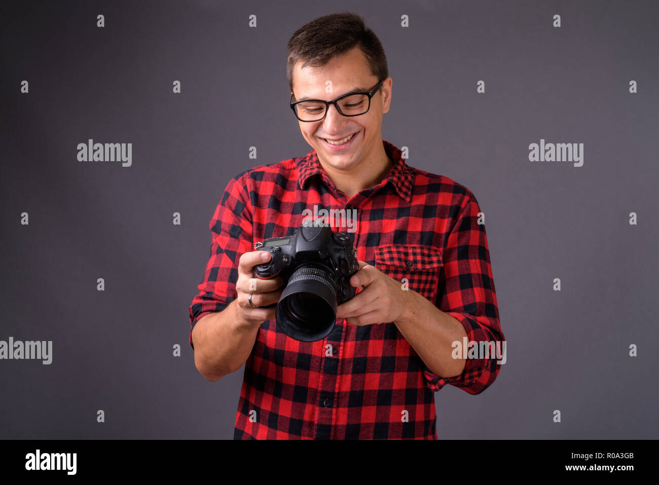 Portrait of young handsome man photographer holding camera Stock Photo ...