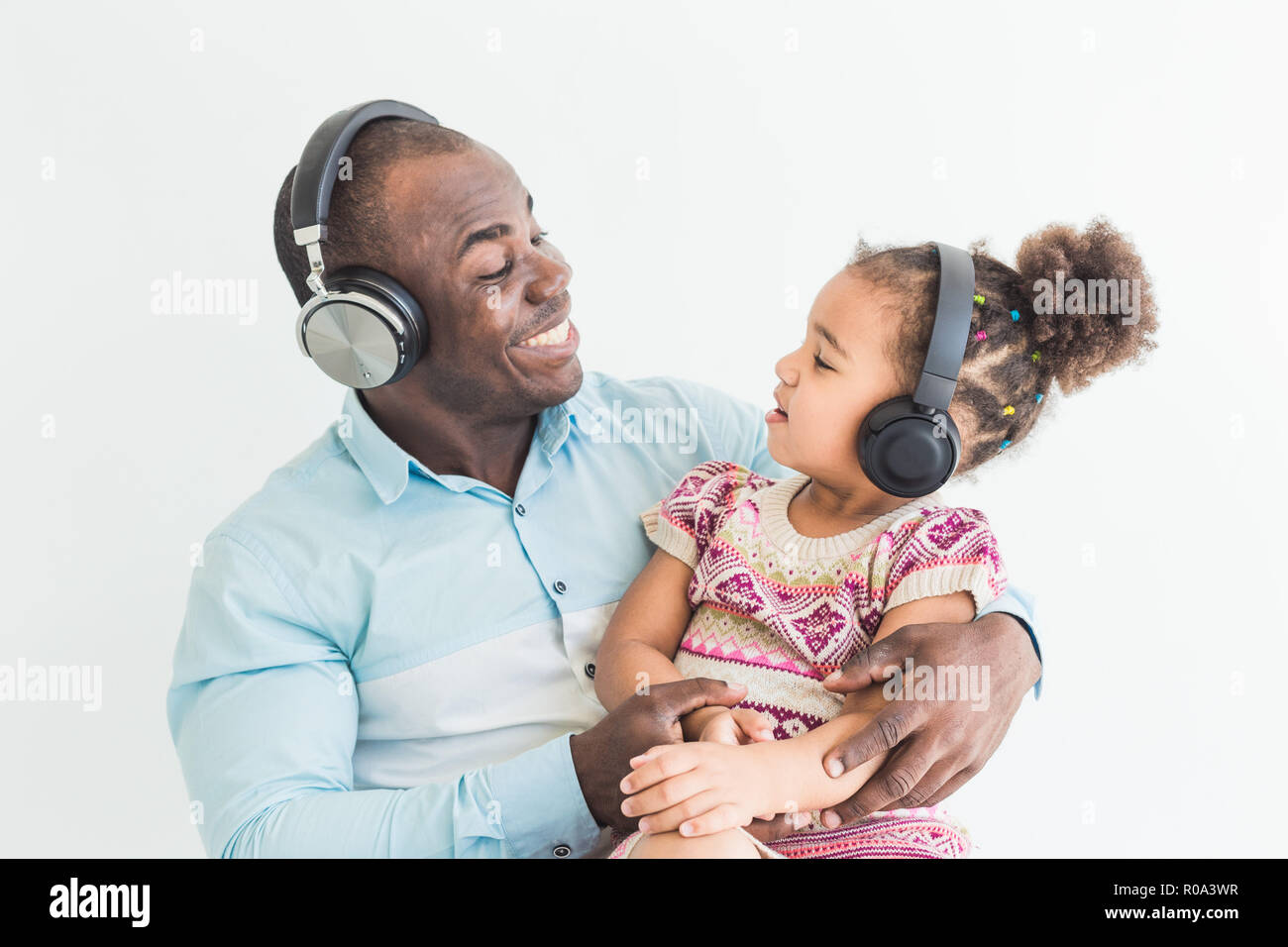Cute little girl and her dad are listening to music with headphones on ...