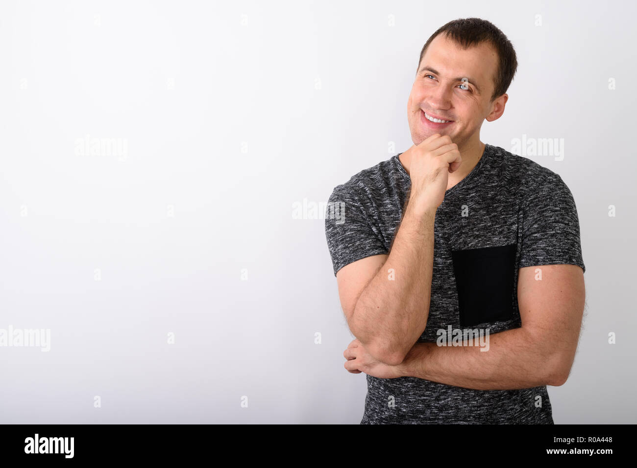 Studio shot of young happy muscular man smiling while thinking a Stock ...