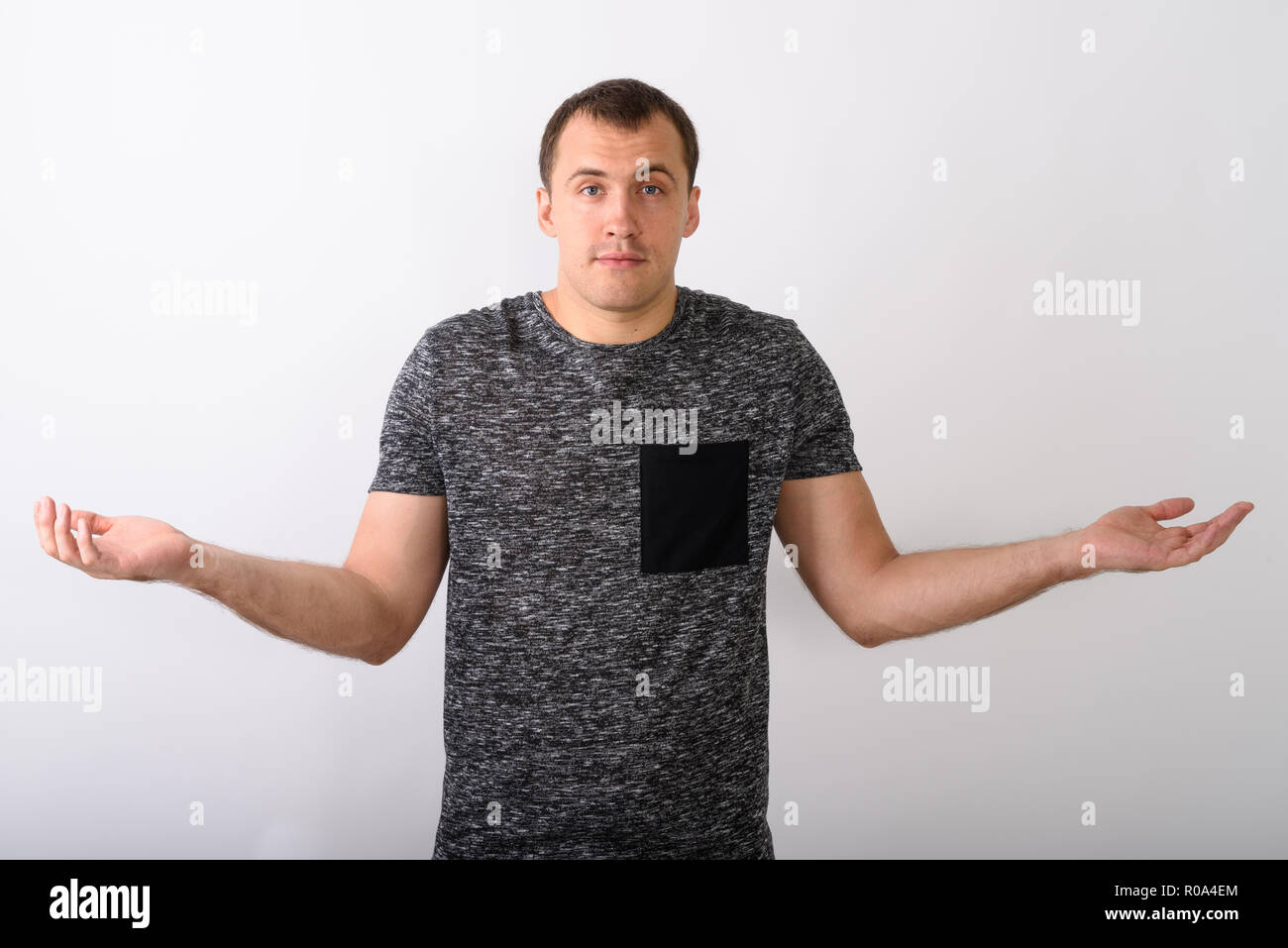 Studio shot of young muscular man looking confused against white Stock ...