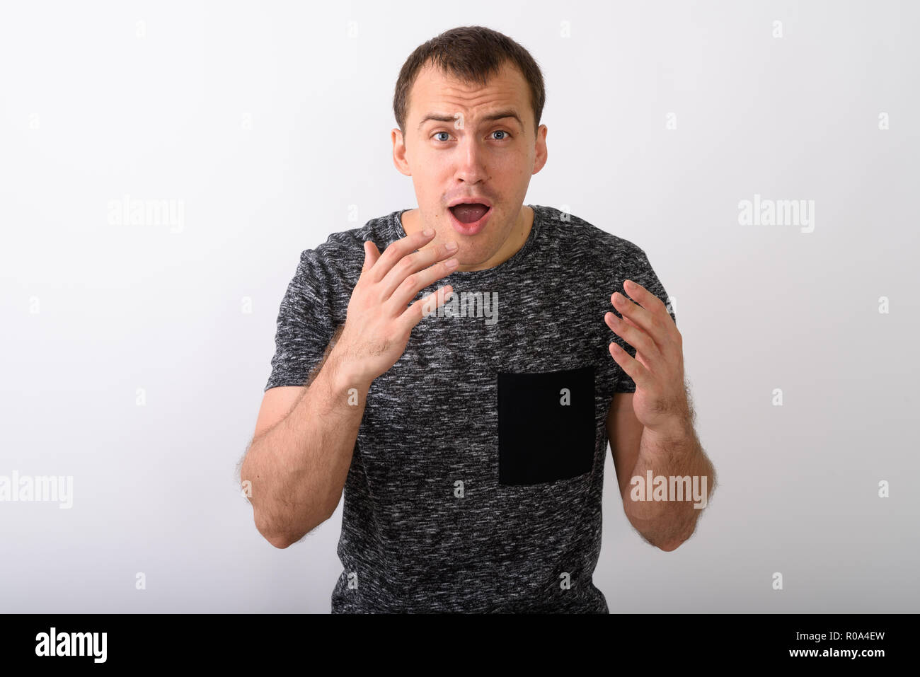 Studio shot of young muscular man looking shocked against white Stock ...
