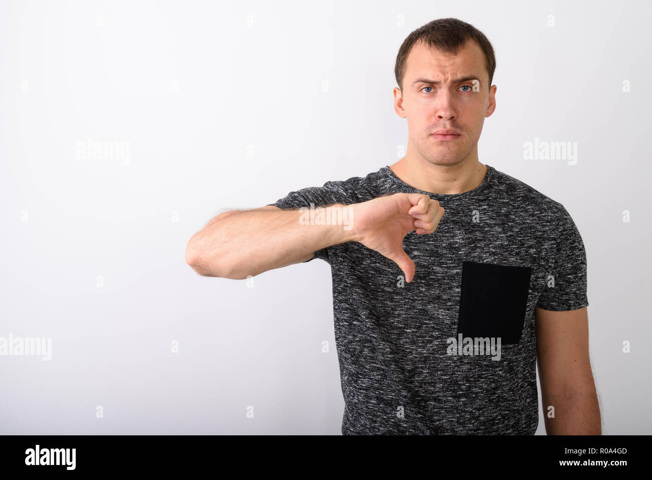 Studio shot of young muscular man giving thumb down against whit Stock ...