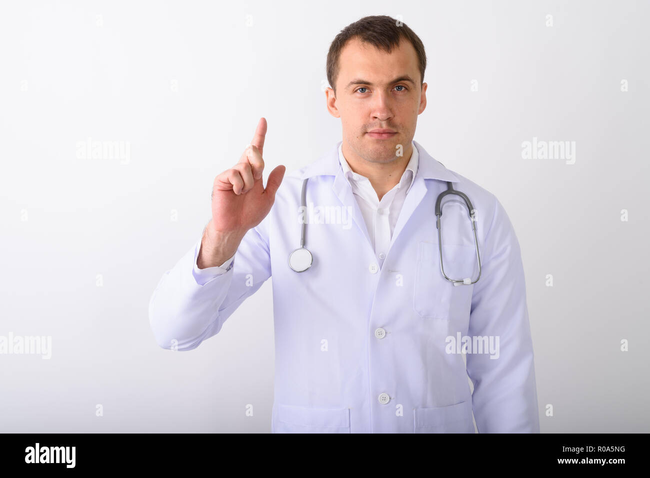 Studio shot of young muscular man doctor pointing finger up agai Stock ...