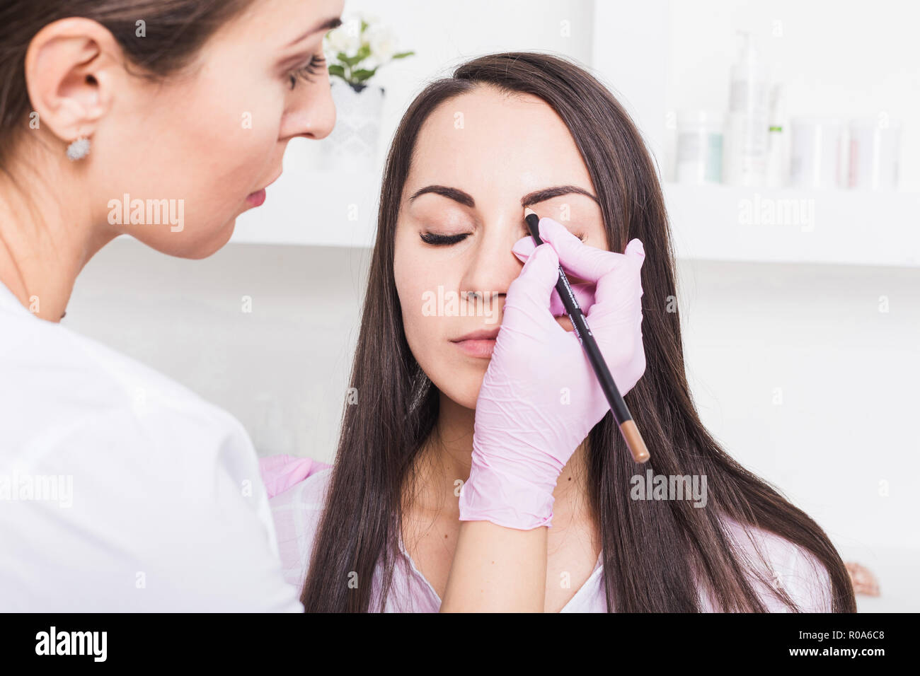 Permanent makeup for eyebrows of beautiful young woman in beauty salon ...