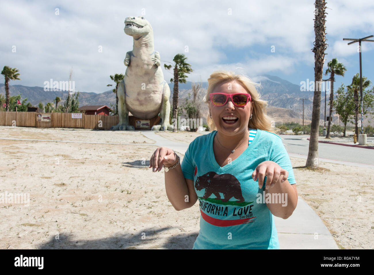 Young woman does t rex arms in front of the Cabazon dinosaurs in Palm ...