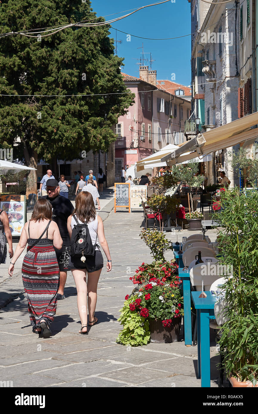 Tourists taking a walk through the historic old town of Porec in Istria ...