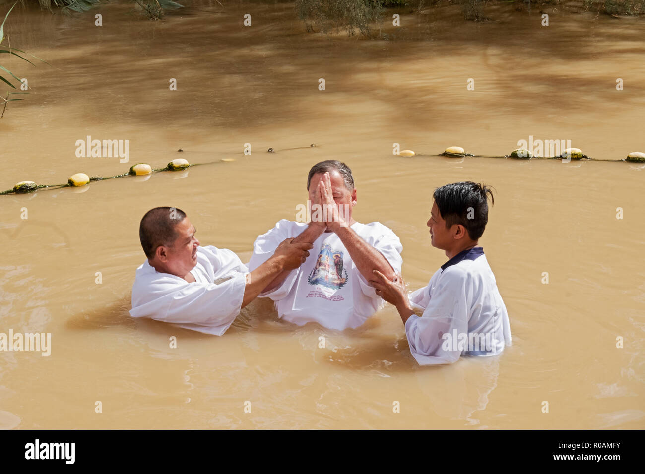 A visitor from the Philippines gets baptized in the Jordan River where ...