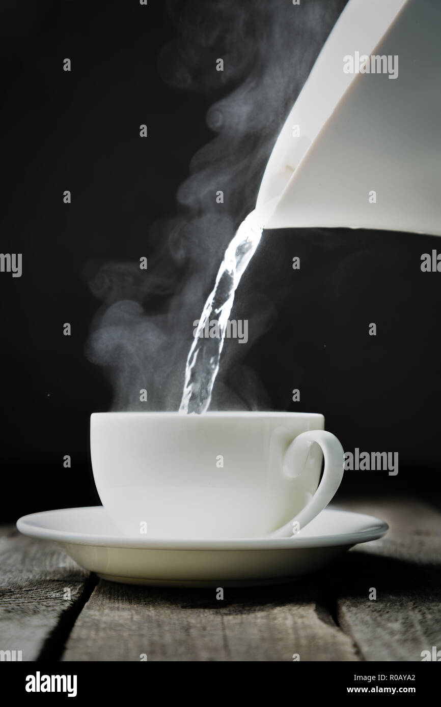 Pouring water in cup, rustic wood background Stock Photo - Alamy