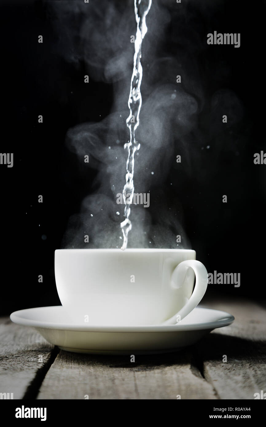 Pouring water in cup, rustic wood background Stock Photo - Alamy