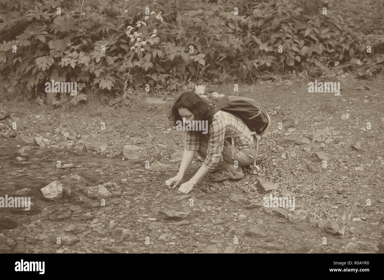 Traveling woman washing her face and hands with water from stream in ...
