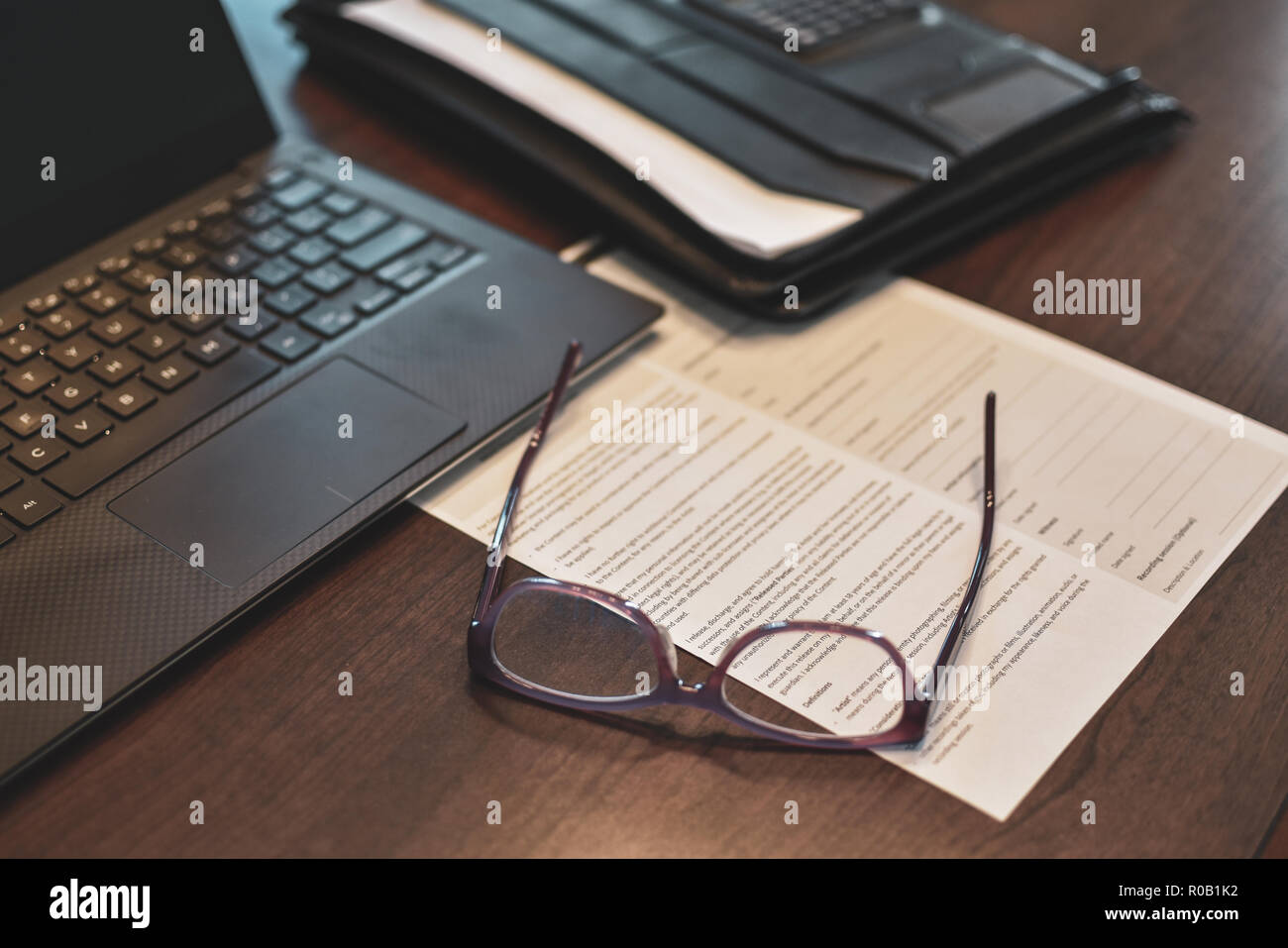 Laptop with glasses and paperwork on a desk Stock Photo - Alamy