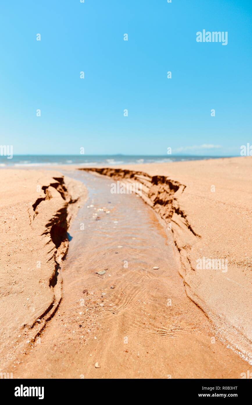 Small stream flowing into the sea on a deserted beach, Balgal beach ...