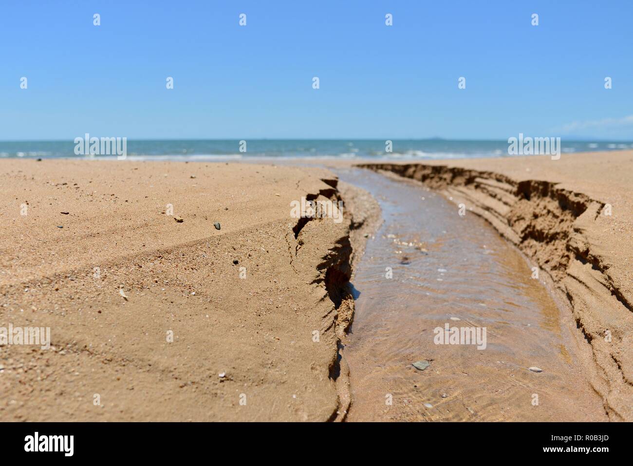 Small stream flowing into the sea on a deserted beach, Balgal beach ...