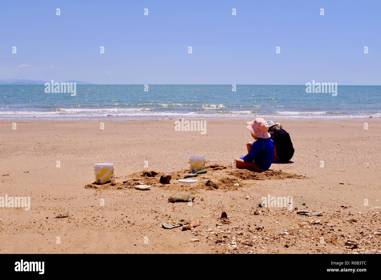 Children playing in the sand with buckets and spades, Balgal beach, QLD ...