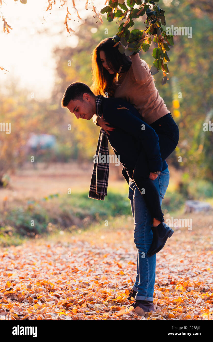 Girlfriend on top of her boyfriends back pulling leaves down on his ...