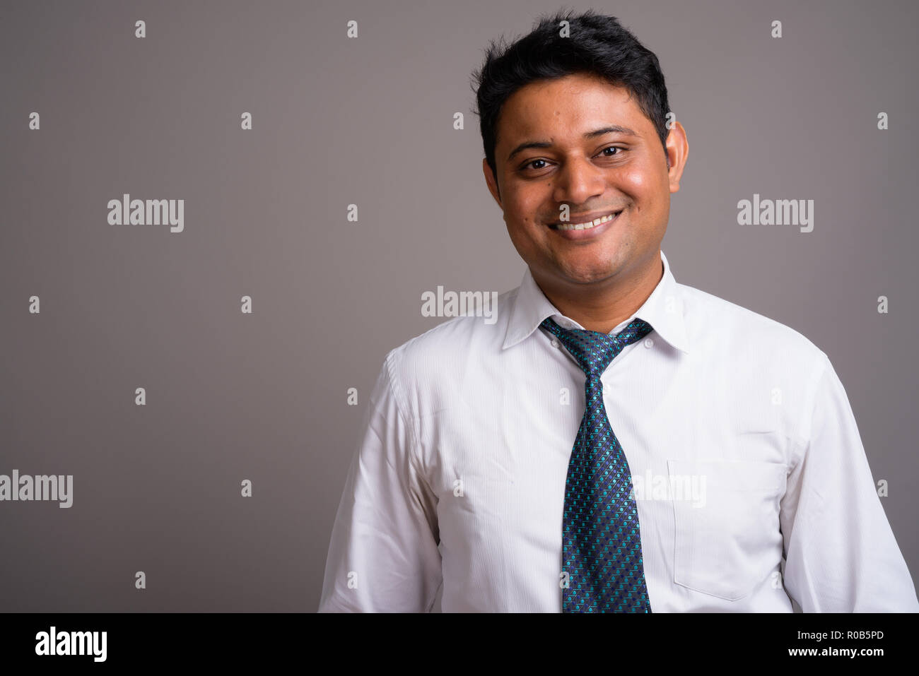 Portrait of young Indian businessman against gray background Stock ...