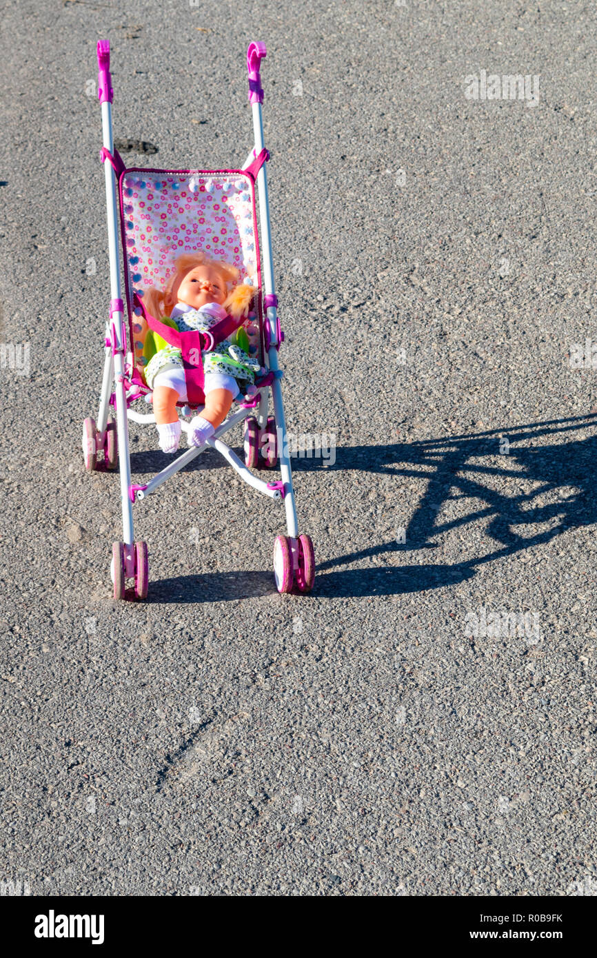 alone Soft doll in a toy carriage, standing in road, danger Stock Photo ...