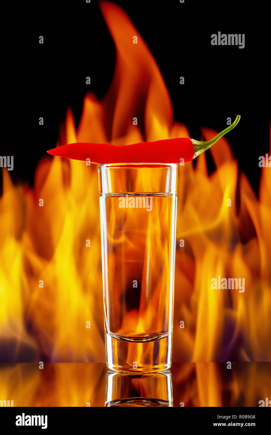 tequila or vodka shot with chili pepper on fire background Stock Photo ...