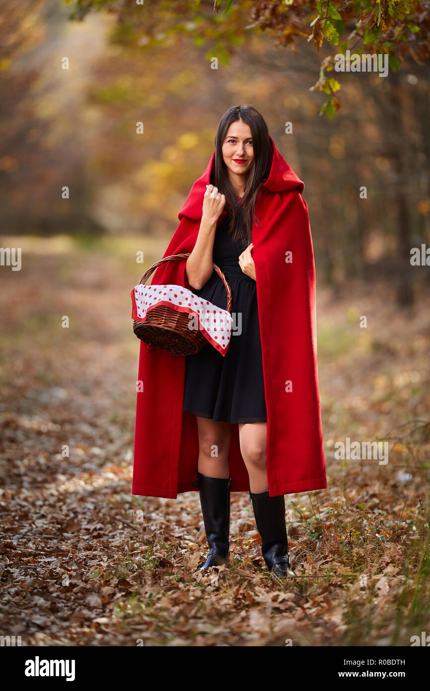 Woman dressed as Red Riding Hood in various postures in the forest ...
