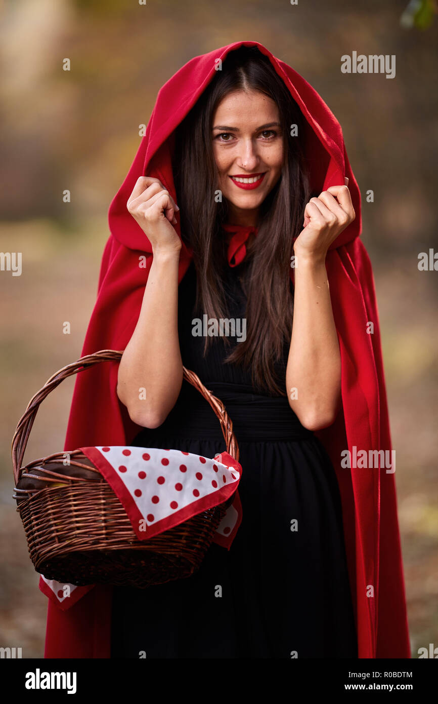 Woman dressed as Red Riding Hood in various postures in the forest ...