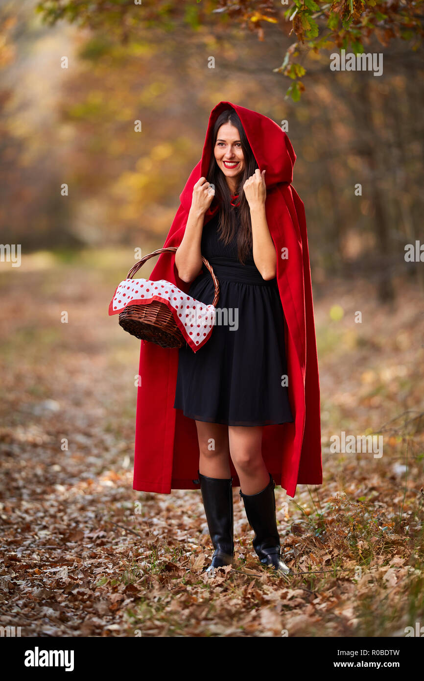 Woman dressed as Red Riding Hood in various postures in the forest ...