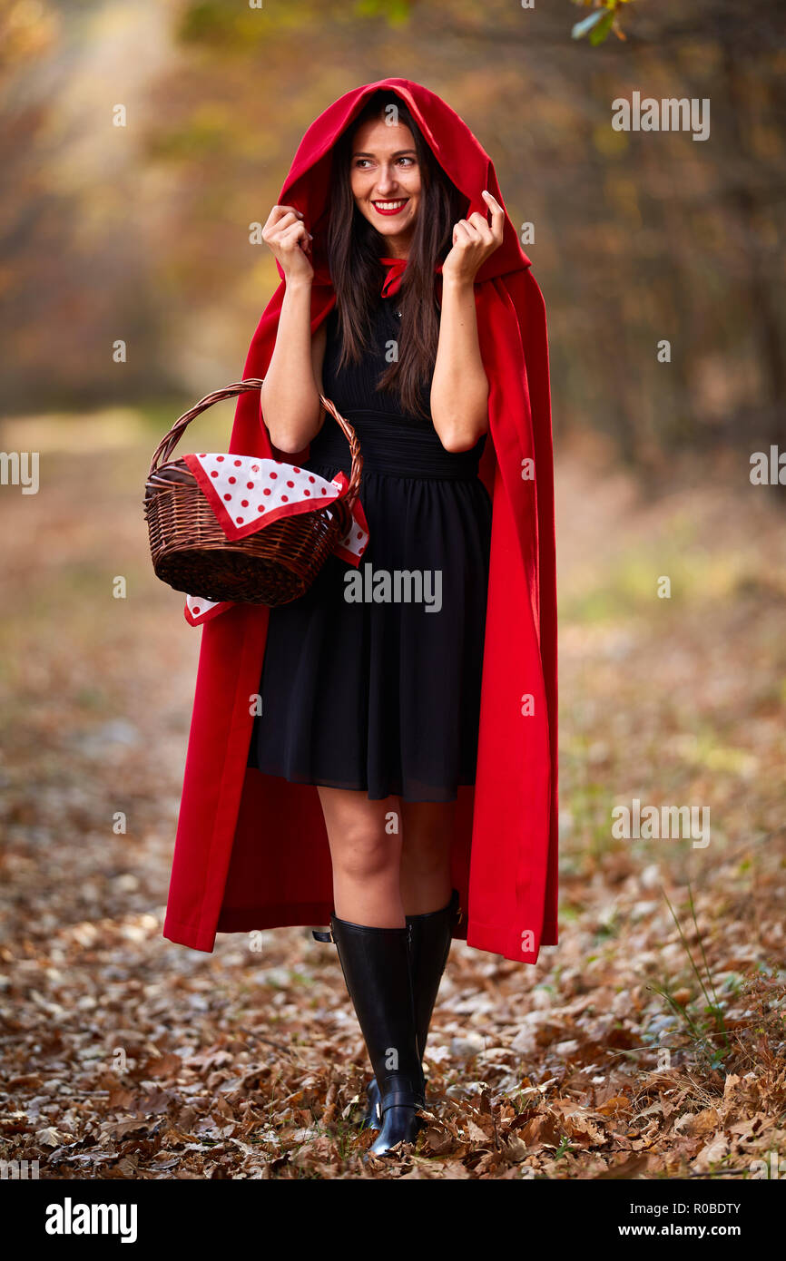 Woman dressed as Red Riding Hood in various postures in the forest ...