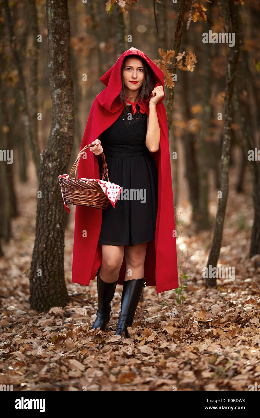 Woman dressed as Red Riding Hood in various postures in the forest ...
