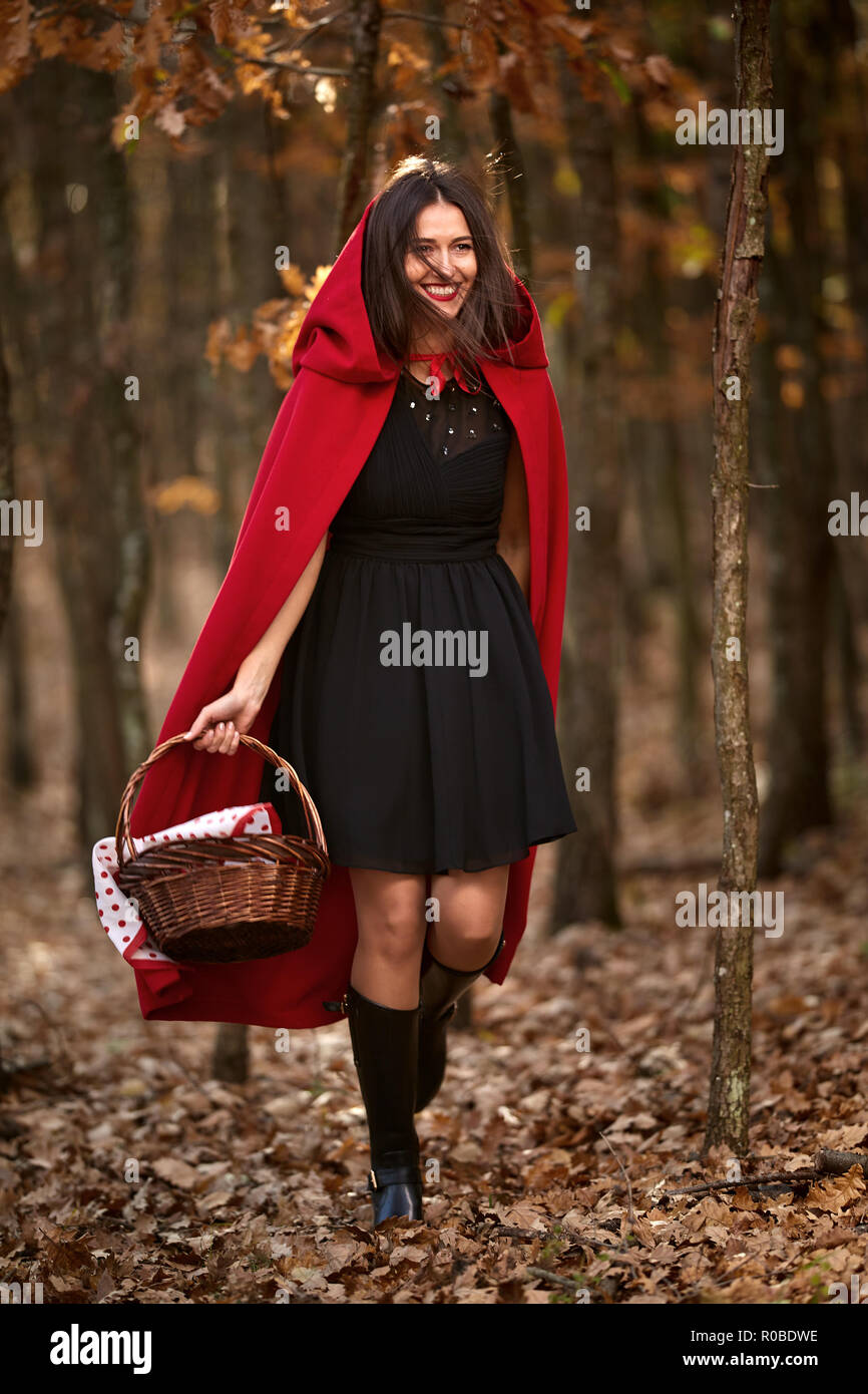 Woman dressed as Red Riding Hood in various postures in the forest ...