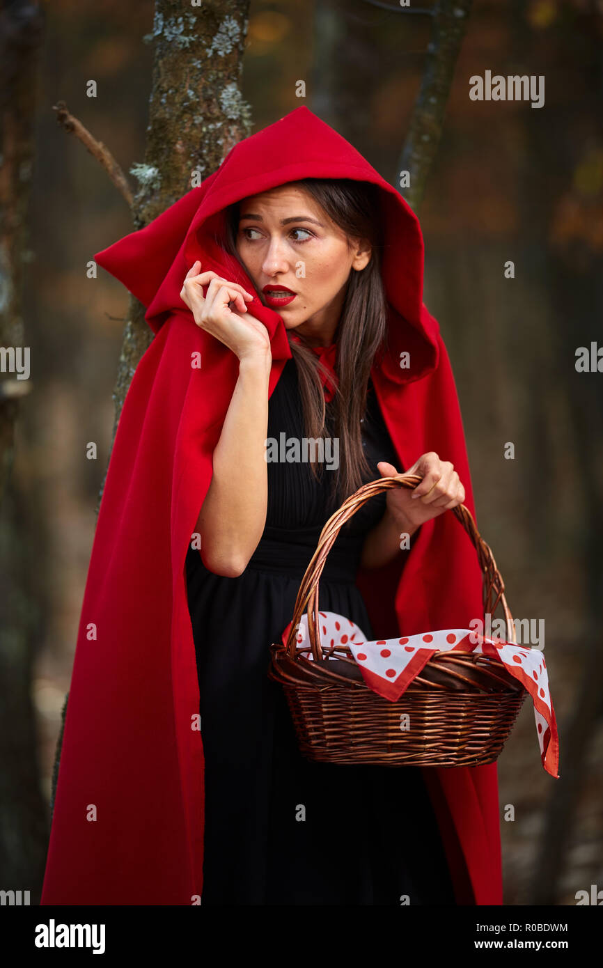 Woman dressed as Red Riding Hood in various postures in the forest ...