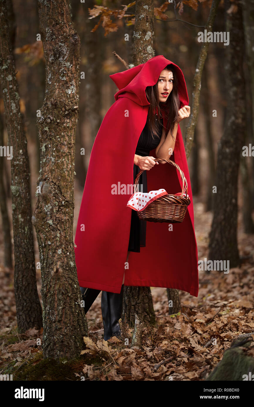 Woman dressed as Red Riding Hood in various postures in the forest ...