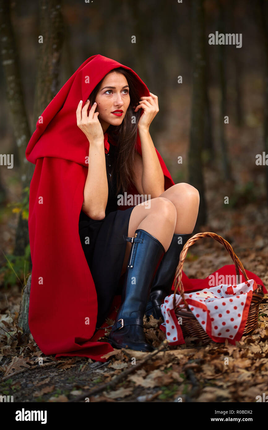 Woman dressed as Red Riding Hood in various postures in the forest ...