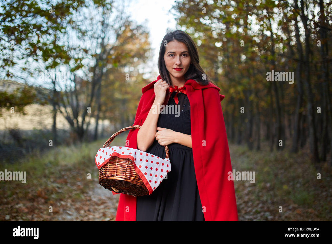Woman dressed as Red Riding Hood in various postures in the forest ...