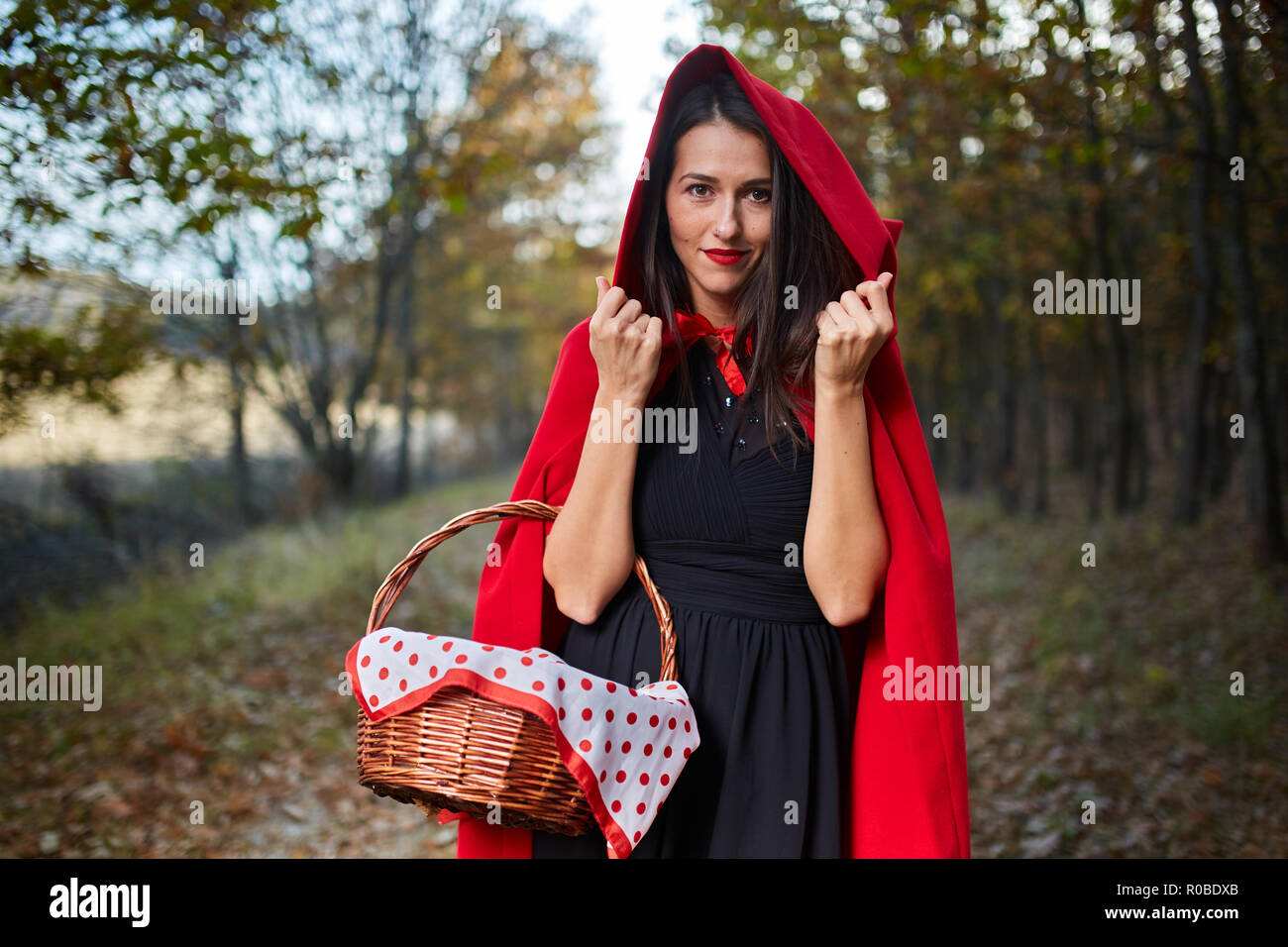 Woman dressed as Red Riding Hood in various postures in the forest ...