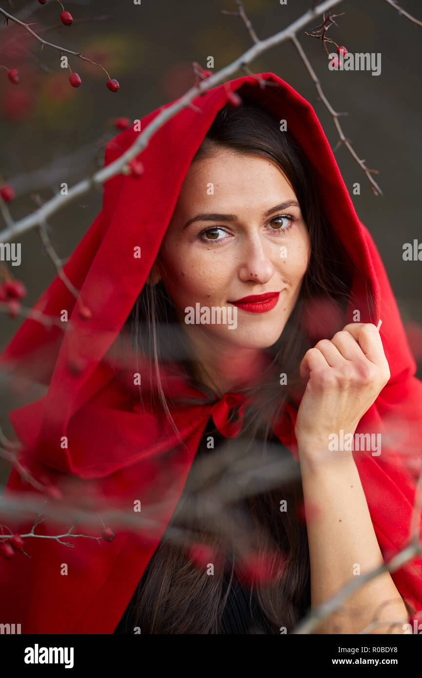 Woman dressed as Red Riding Hood in various postures in the forest ...