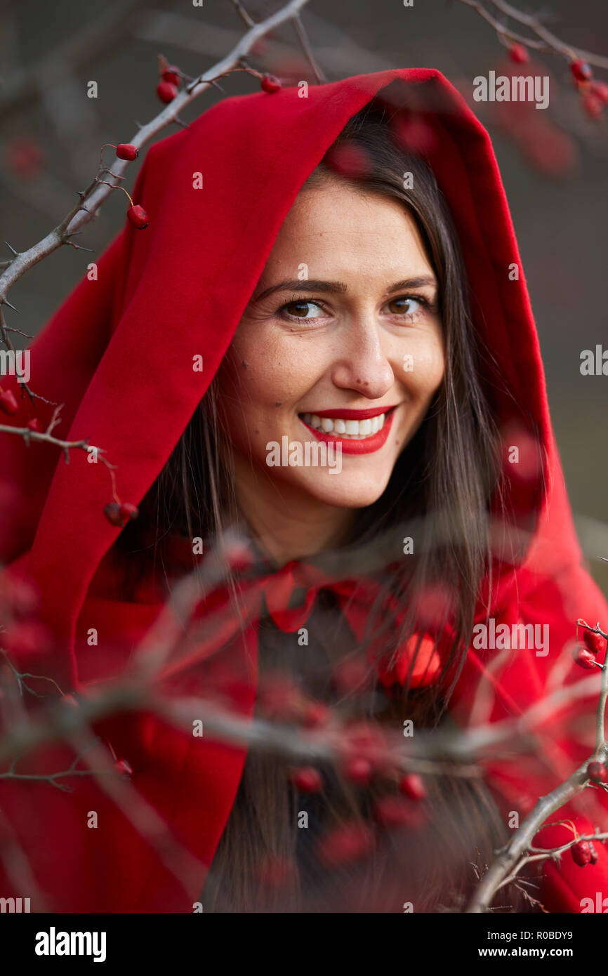 Woman dressed as Red Riding Hood in various postures in the forest ...