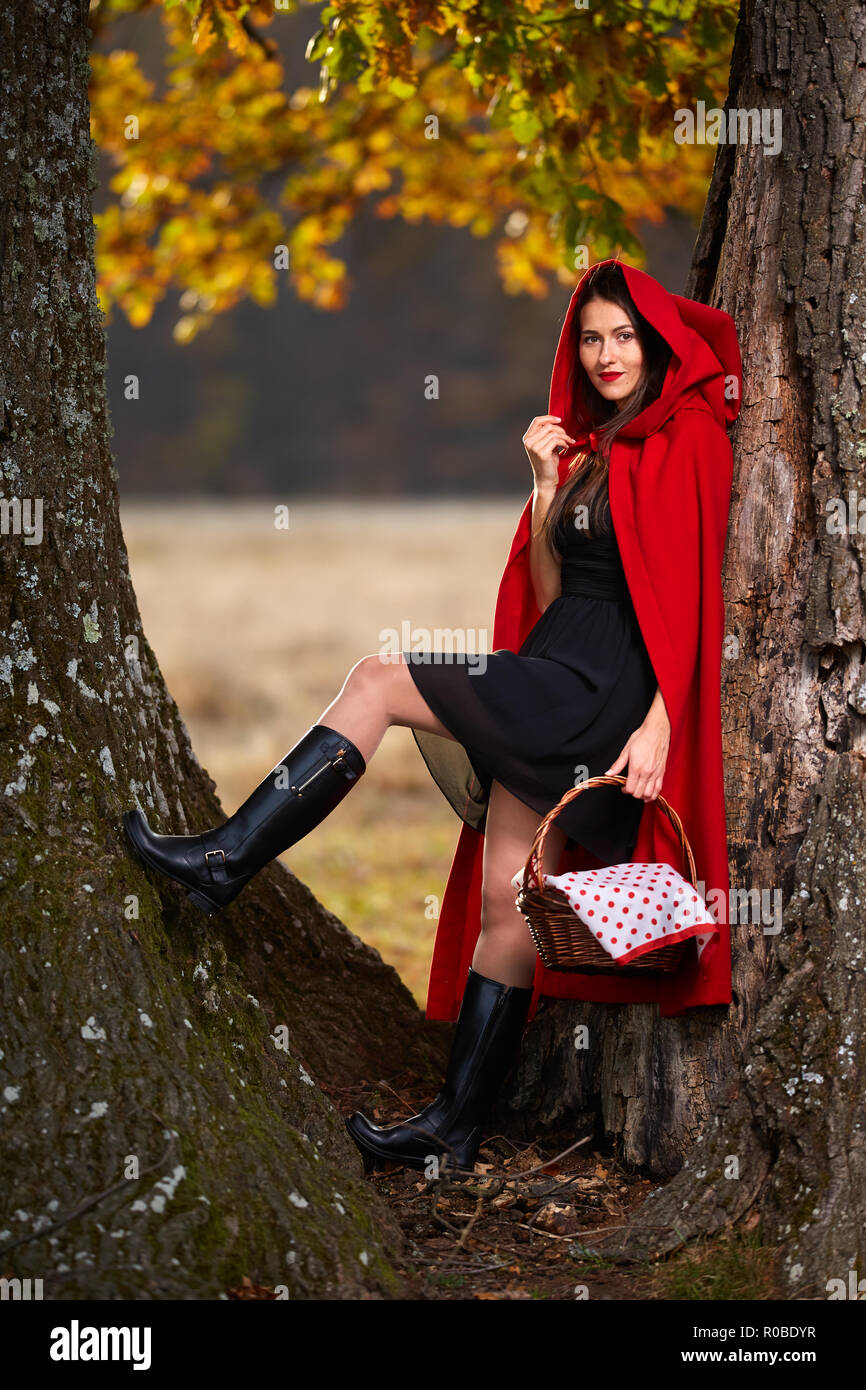 Woman dressed as Red Riding Hood in various postures in the forest ...